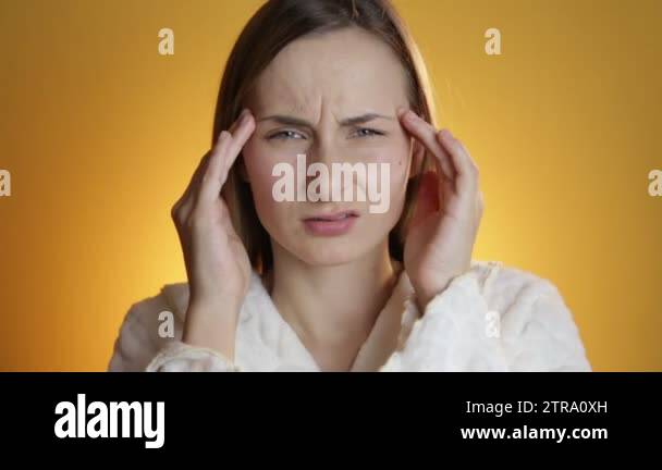 Young sad woman with headache massaging her temples with circular ...