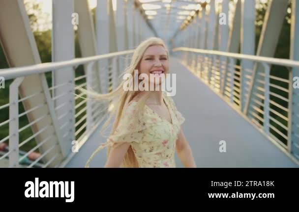 Woman throwing up hair on bridge. Back view of blonde woman running on ...