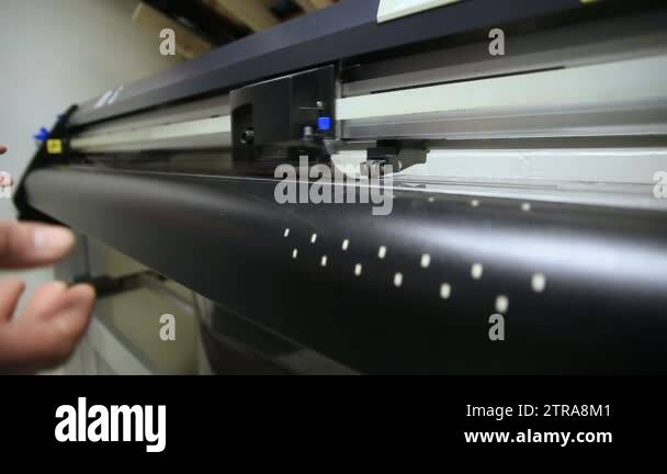 machine which cuts the film for gluing. Employee service takes plotter ...