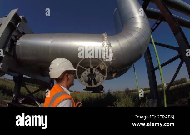 The engineer opens and closes the valve on the industrial pipeline for ...