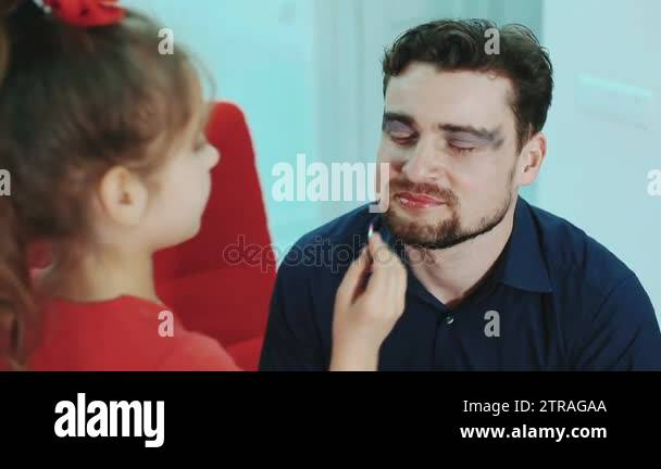 Funny family. Father and his child daughter girl paints lips to her ...