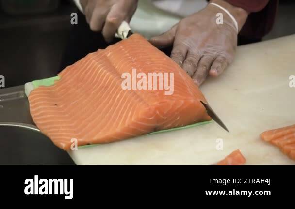 Process of making and cutting salmon for sushi rolls. Cook cutting up ...