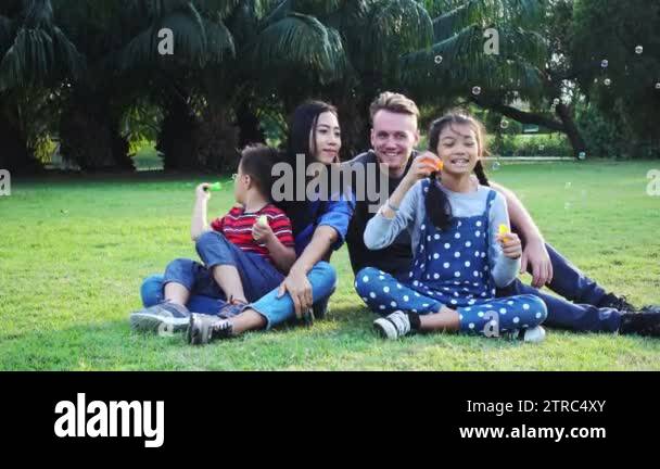 Family blowing bubble in park. Mixed race family with white man ...