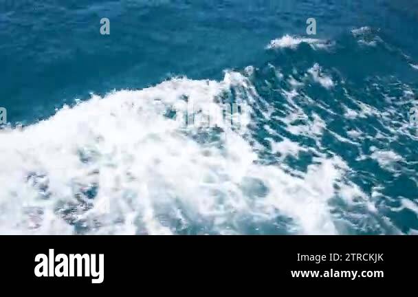 Close up background of vivid indigo blue sea water waves running aboard ...