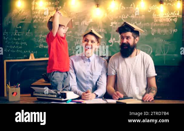 Two adults and a boy with books on the head are entertaining in the ...