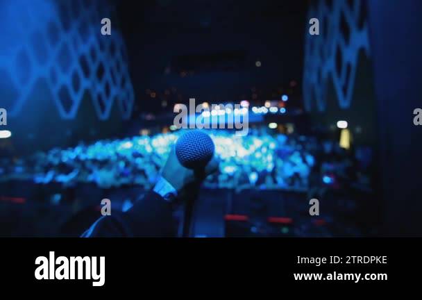 Singer's hands grabbing microphone on a stand while on stage with crowd ...