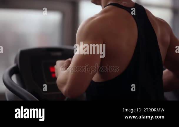 Back and side view of a strong bodybuilder running on a treadmill while ...