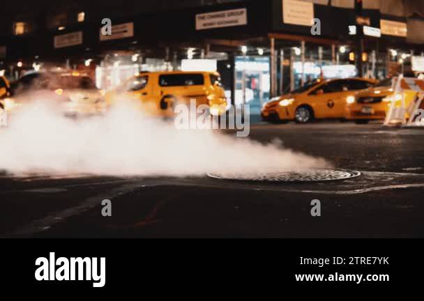 Close-up view of smoke coming from manhole cover on the traffic road in ...