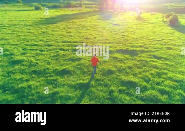 UHD 4K aerial view. Low altitude flight near sporty man running at ...