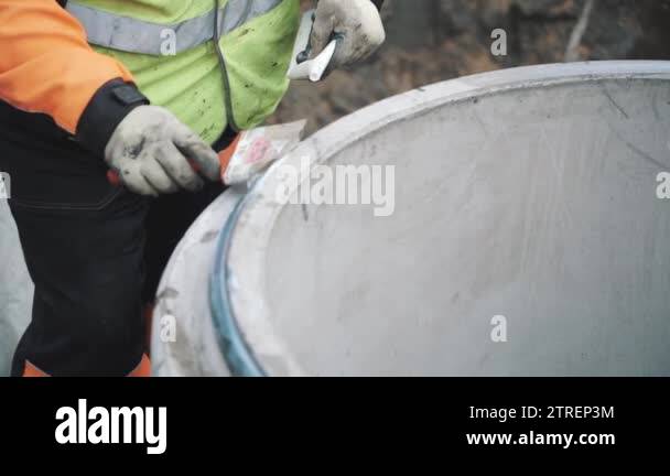 Builder put white glue on edge of concrete manhole ring with brush ...