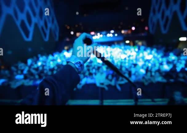 Singer's hands grabbing microphone stand on stage with a crowd and fans ...