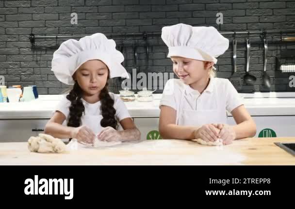 Cooking makes fun. Two little kids cook together , rolling doudh with ...