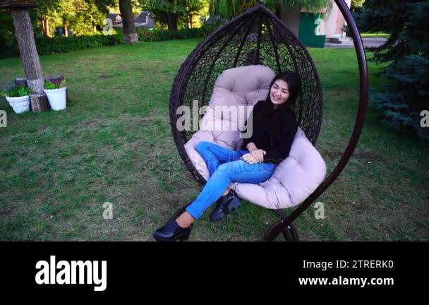 Pretty Woman Sits Comfortably in Chair Suspended by Putting One Foot ...
