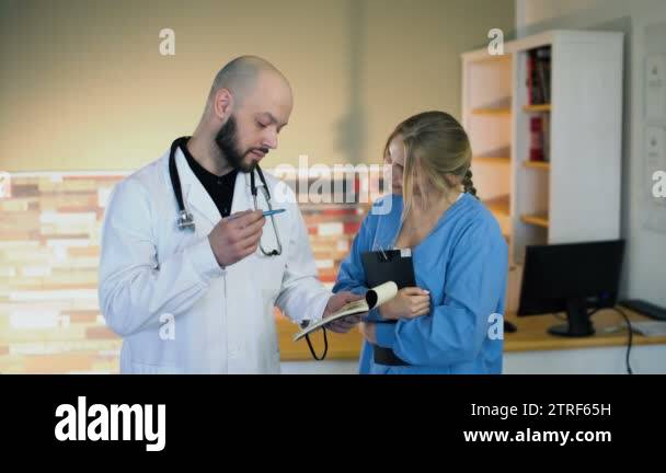 30s bald doctor duscuss with 20s blonde nurse in medical uniform at ...