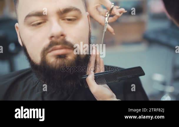 Female barber cuts the beard hair of the male client 4K Stock Video ...