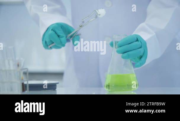 Female medical research scientists put dry ice into a glass beaker ...