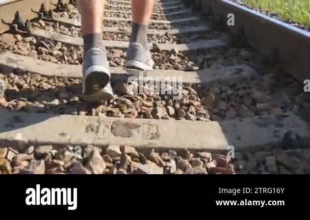 Male feet are running between rails on railroad tracks. Sprinting ...