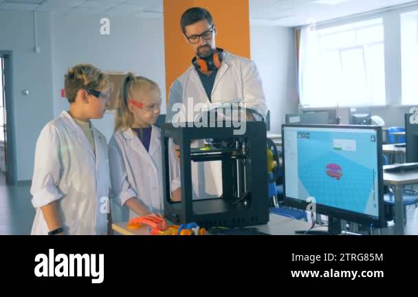Interaction between a lab worker and two kids while managing 3D printing Stock Video Footage - Alamy