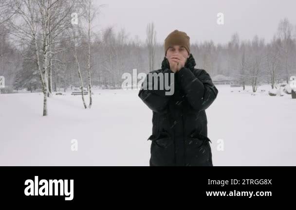 A young man in winter is cold in the forest. Big snowfall. Hes ...