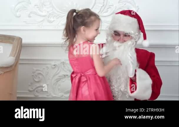 Santa Claus clapping his hands while pretty little girl dancing around ...