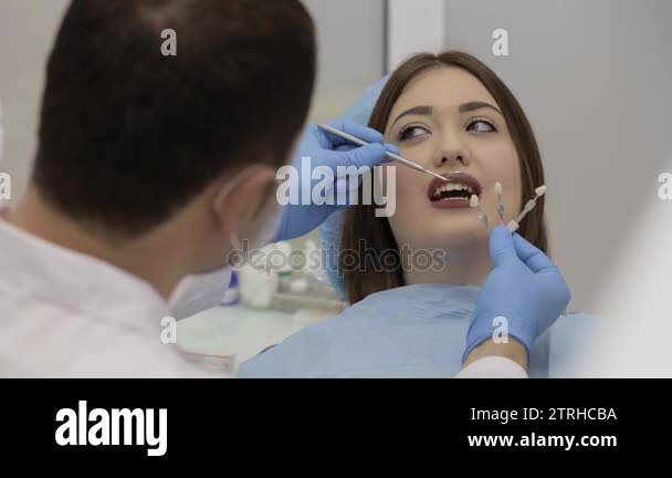 Dentist check and select the color of the teeth of young female patient ...