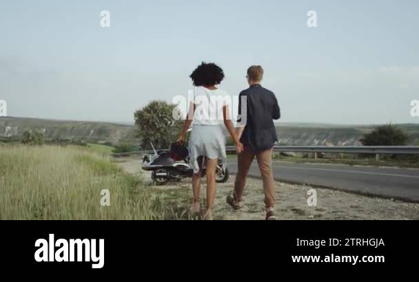 Friends after taking a walk, go towards a motorcycle and approach the ...