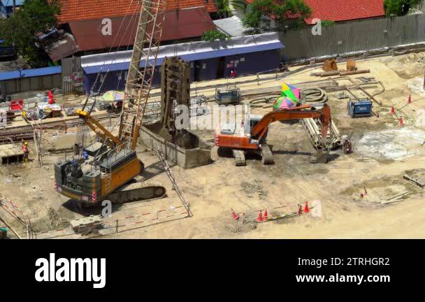 excavator digging holes for foundation of building construction site ...