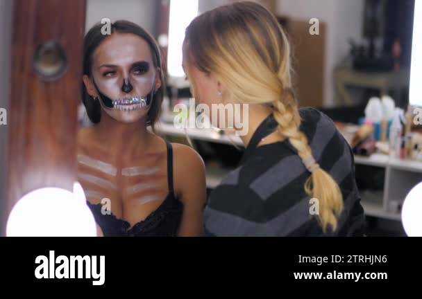 Makeup artist paints greasepaint for Halloween in studio.Woman drawing ...