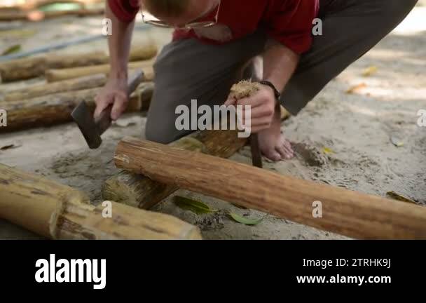Young man prepares wood to build home construction by traditional way ...