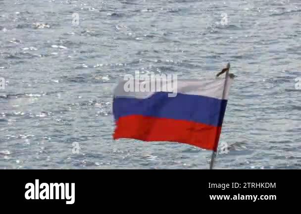 Russian flag waving in the background of the glare on the water. Stern ...