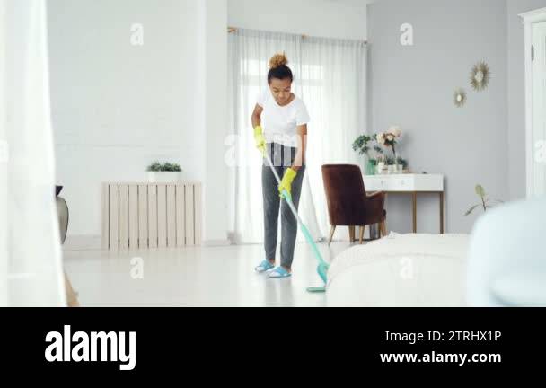 Pretty African American girl is mopping floor at home with flat plastic ...