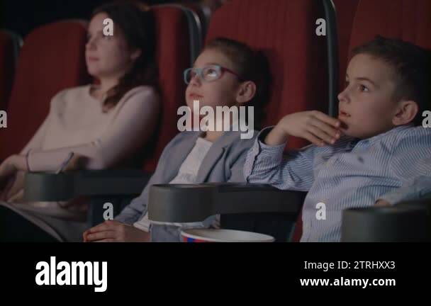 Kids are frightened at movie theatre. Scared children cover faces by ...