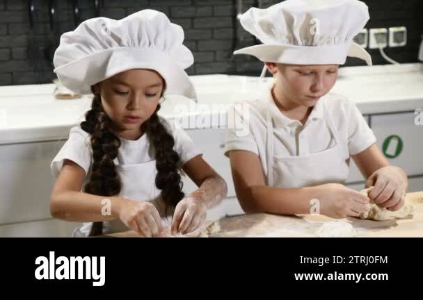 Cooking together. Two children in chef hat rolling dough in home ...
