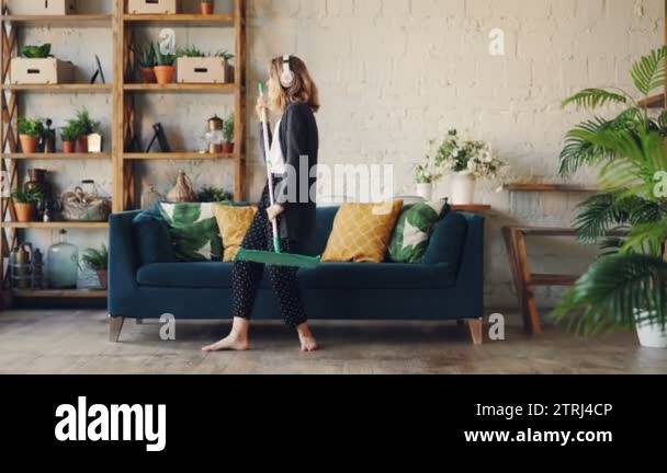 Funny young woman is singing in mop then pretending to play the guitar ...