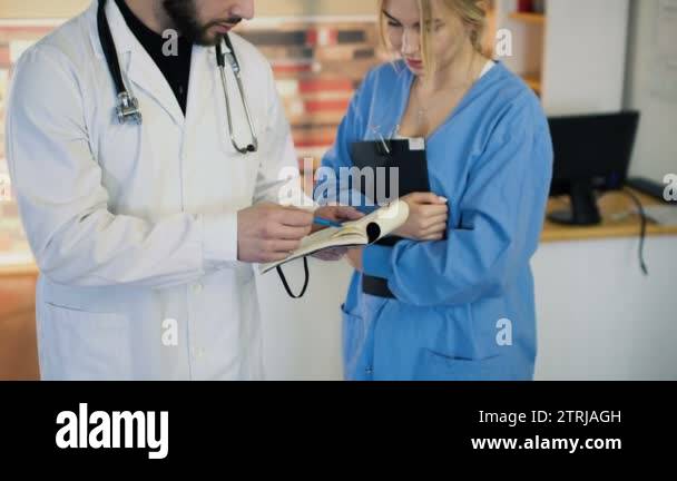 30s bald doctor duscuss with 20s blonde nurse in medical uniform at ...