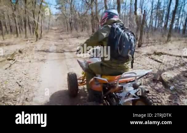 A young teenager is riding a four-wheeled quad ATV on a country road, a ...