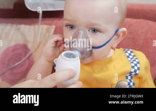 Mother holds the mask on the baby inhaler and breathes the medicine at ...