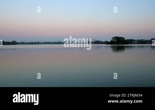 The calm surface of Inya lake reflects the clear sunset sky, silhouette ...