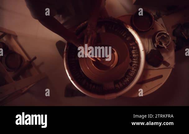 Process of shaping clay dish on rotating potters wheel in dark light ...