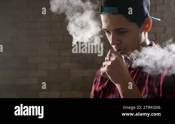 A brown haired nineteen year old boy starts vaping using an e-cigarette ...