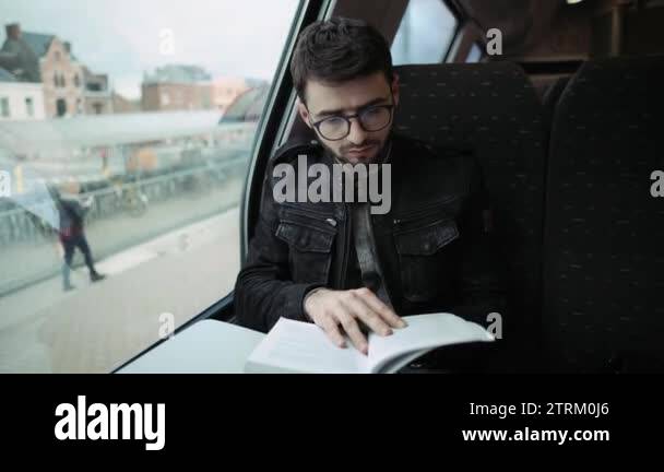 A young boy walking on a train, reading a book. Boy with glasses. 4k ...