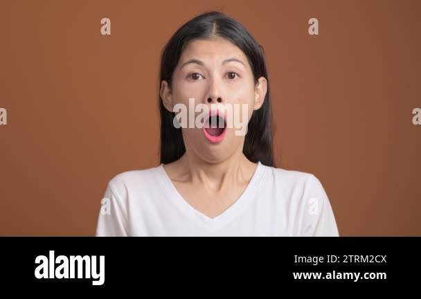 shocked asian woman with open mouth putting hands on cheeks Stock Video ...
