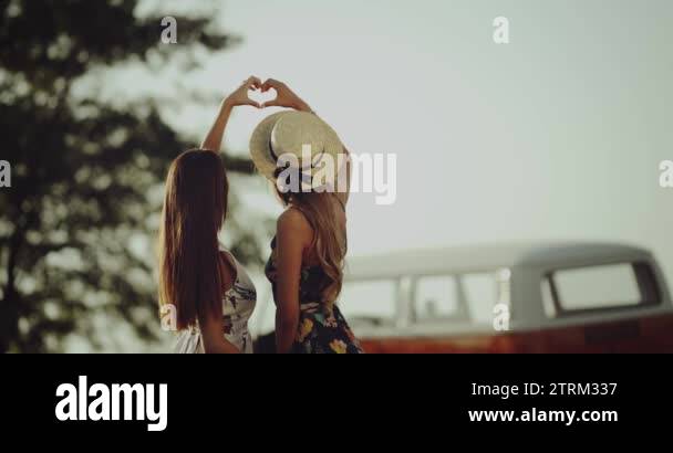 Young two women from 90 s in the middle of nature with their retro bus ...