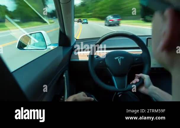 Person driving a new Tesla Model 3 in autopilot. The model 3 is set to ...