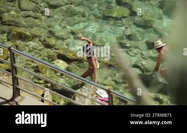 People bathe and rest on the city beach. Girls in a bikini goes along the seashore in a ...