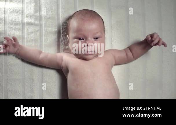 Pretty baby lying on diaper actively wiggles arms and turns his head ...