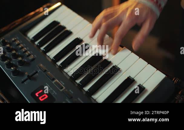 Male in kosovorotka shirt hand fast tapping on keys of midi controller ...