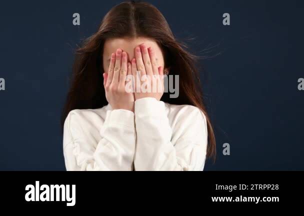 Beautiful happy little girl closes and opens his hands over his face ...