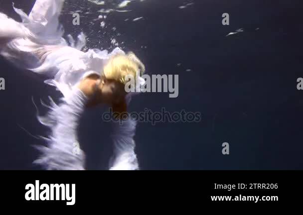 Underwater model free diver in costume angel swims in clean water in ...