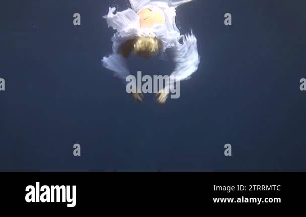 Underwater model free diver in costume angel swims in clean water in ...